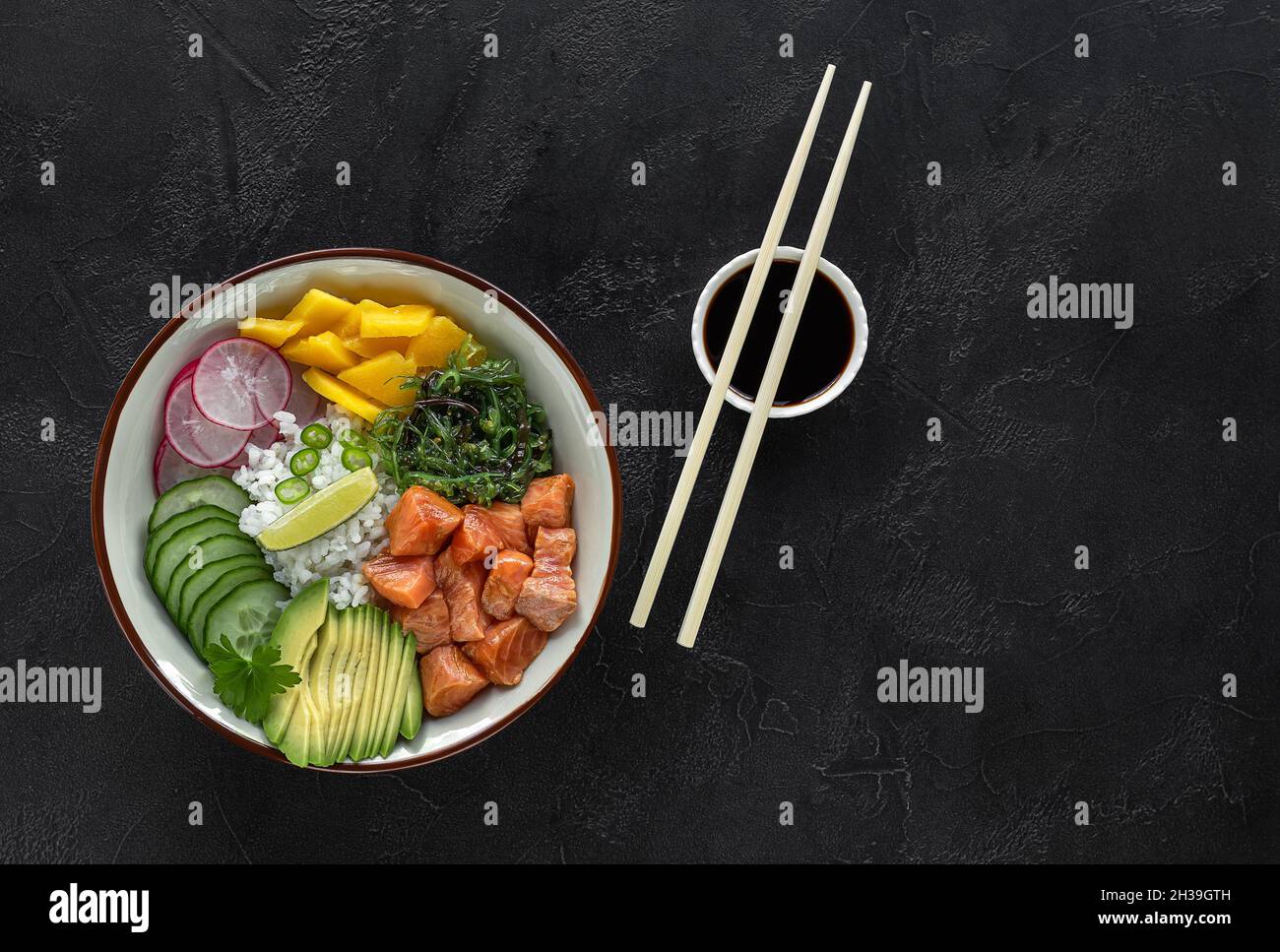 Salmon poke bowl with rice, mango, avocado, seaweed, radish, and ...