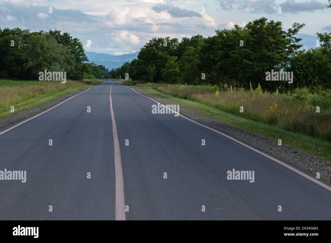 A suburban asphalt road with three solid lines of pink road markings ...