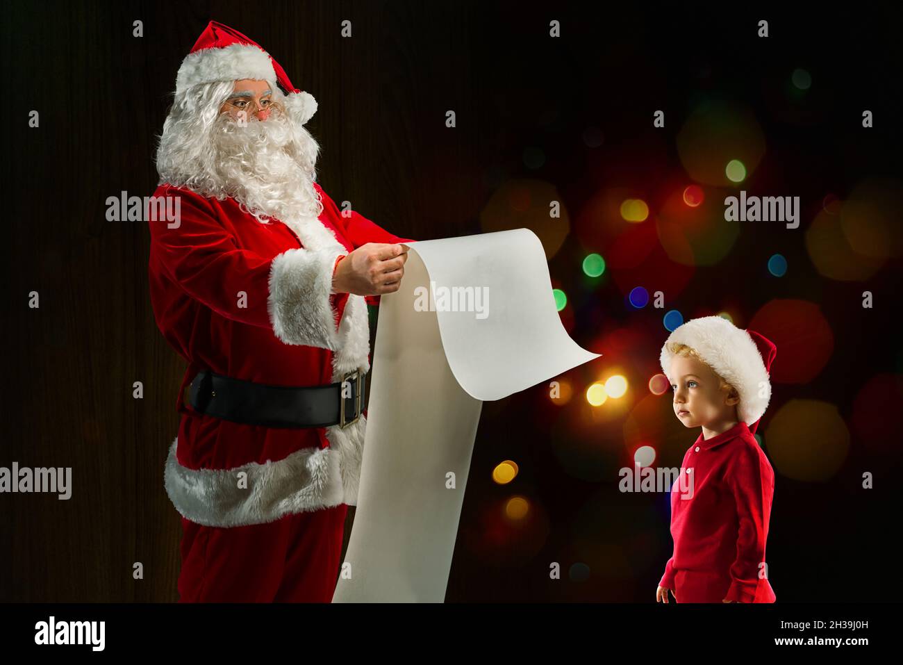Santa Claus searches from a list a gift for a child Stock Photo - Alamy