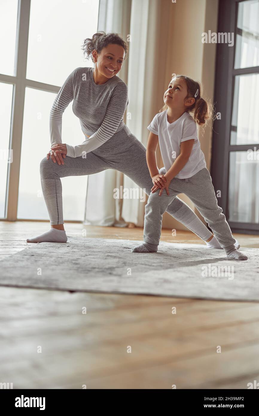 Jolly woman enjoying home workout with daughter Stock Photo - Alamy