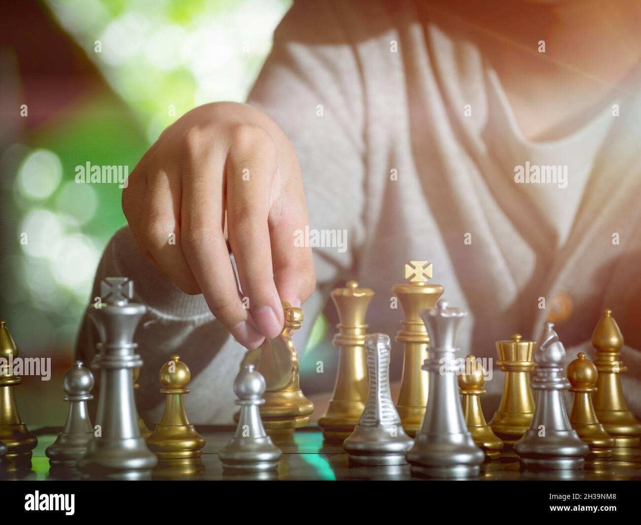 Hand businessman moving the golden knight chess fighting silver knight ...