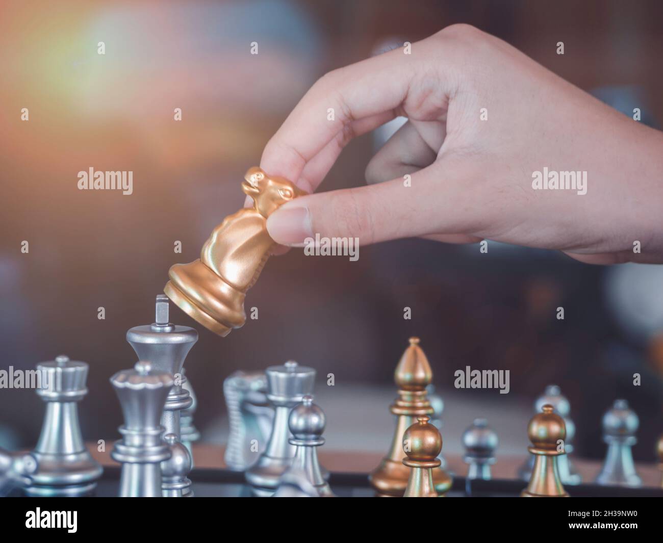 Hand businessman moving the golden knight chess fighting silver knight ...