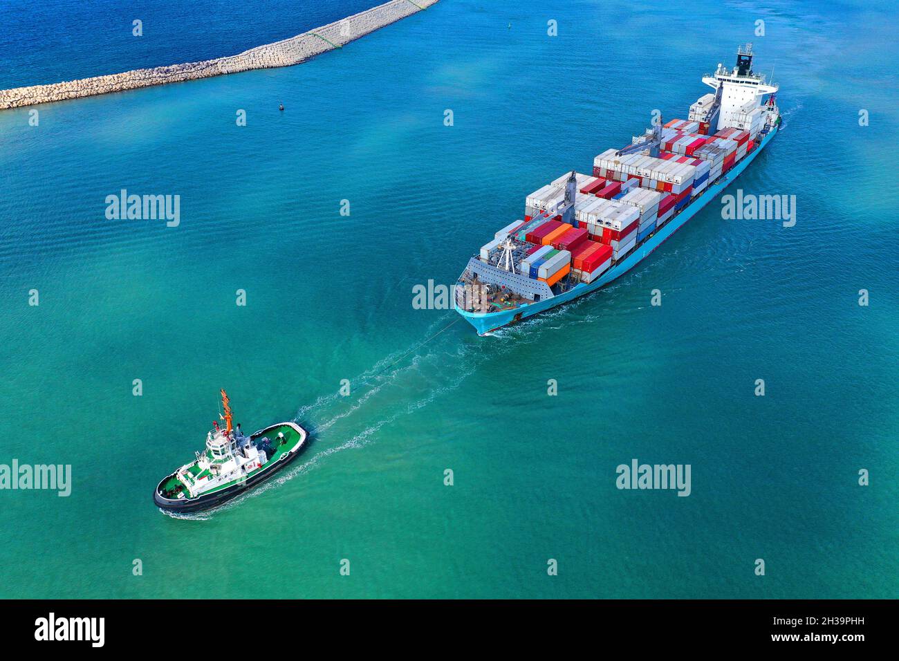Tug boats directing a Container ship into a port dock Stock Photo - Alamy