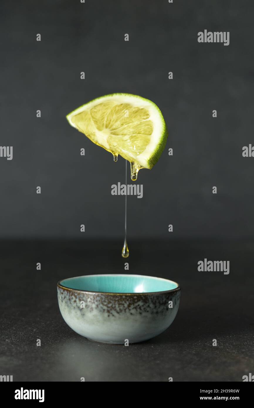 wedge of lime hovers over small bowl, food concept Stock Photo - Alamy