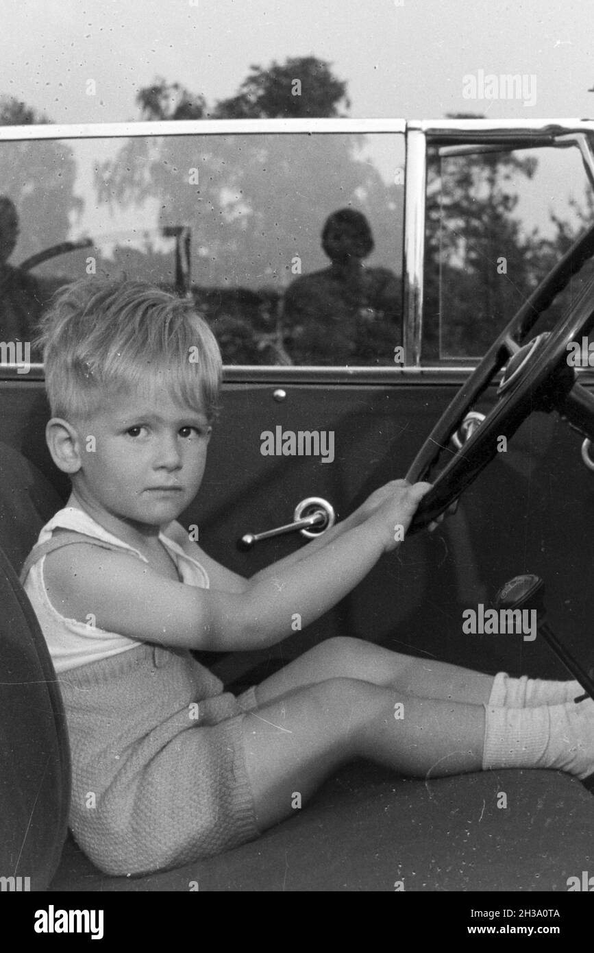 Ein kleiner Junge am Steuer eines Autos, Deutschland 1930er Jahre. A ...