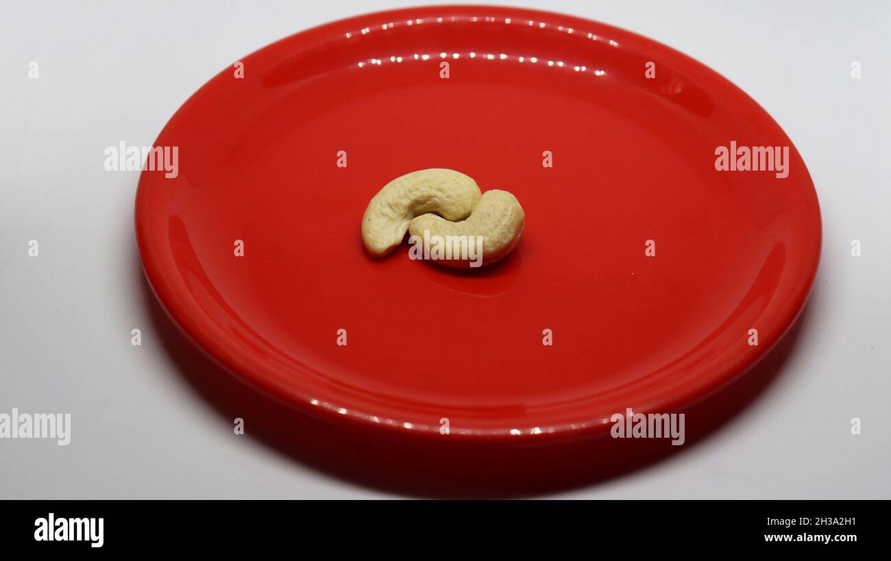 two cashew nuts is on a white background on a red plate Stock Photo - Alamy