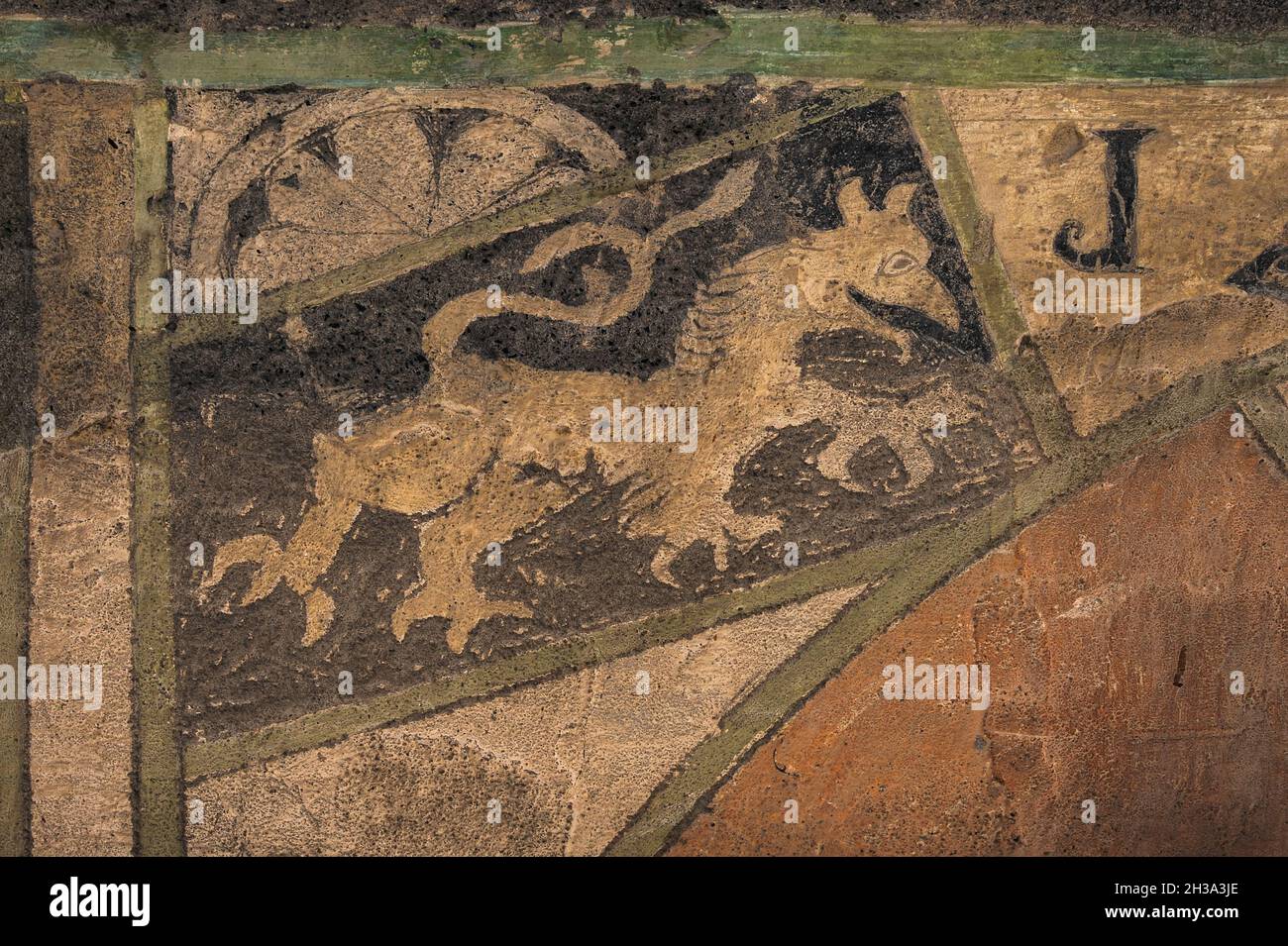 A sgraffito dragon with curved claws and a curled tail snarls from the ...