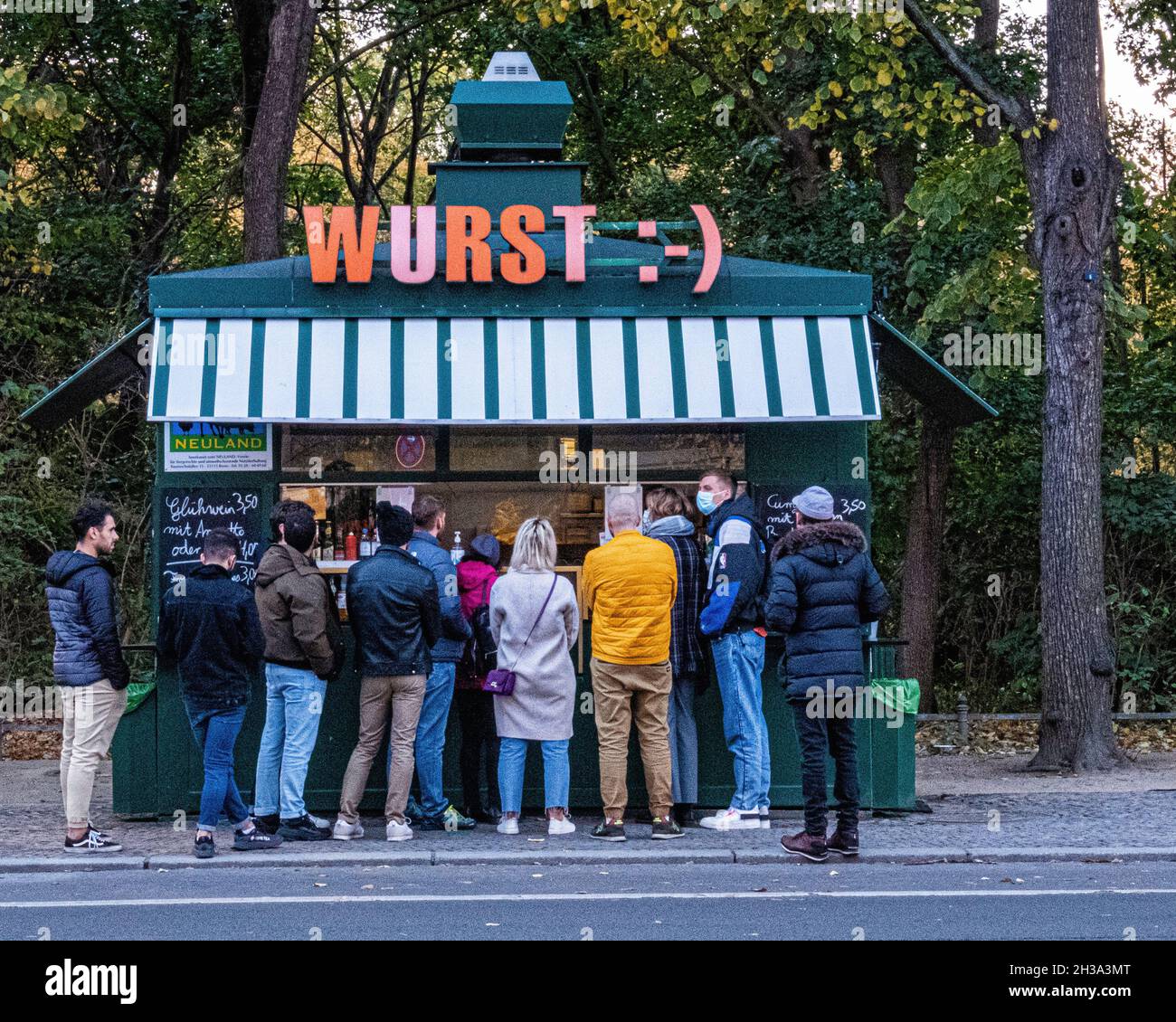 People queue at Wurst fast food kiosk, stall selling sausages ...