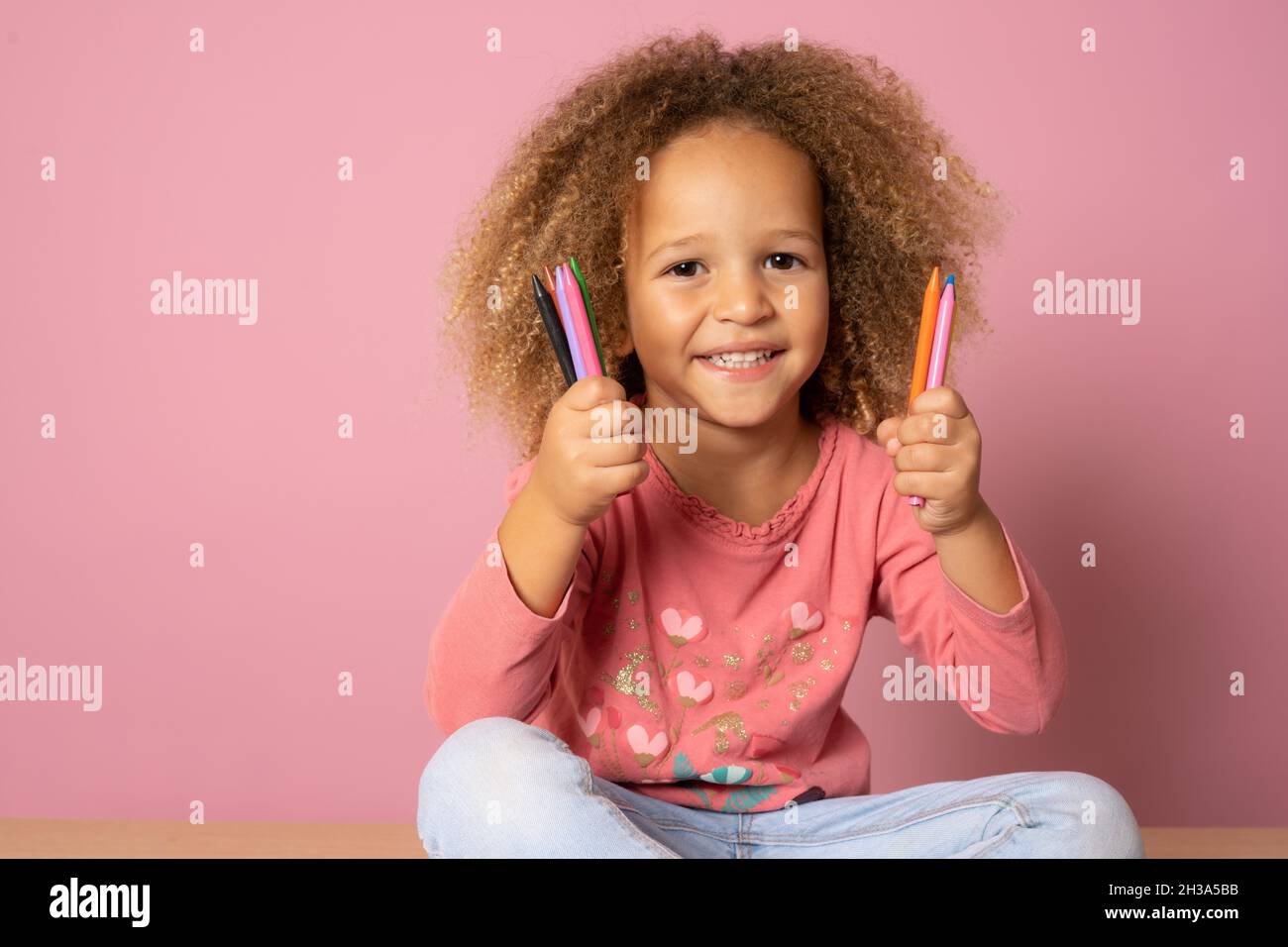 Beautiful little girl holding multicolor crayons set in art school ...