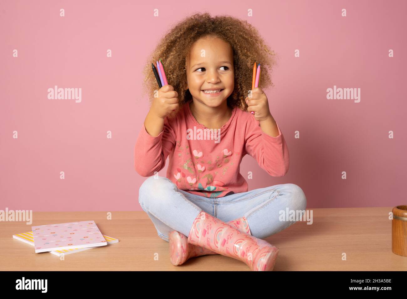 Beautiful little girl holding multicolor crayons set in art school ...