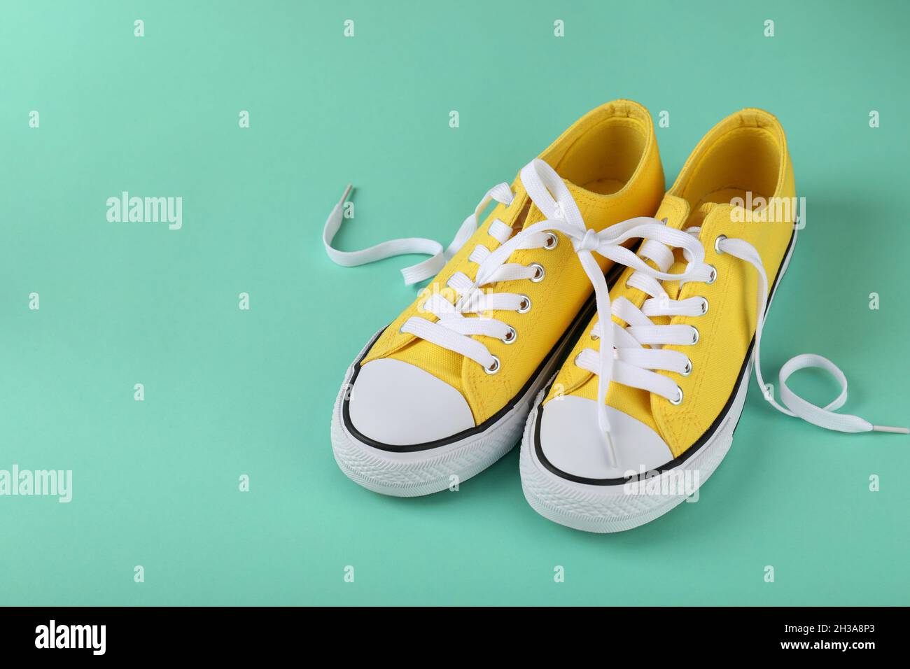Pair of yellow sneakers on mint background Stock Photo - Alamy