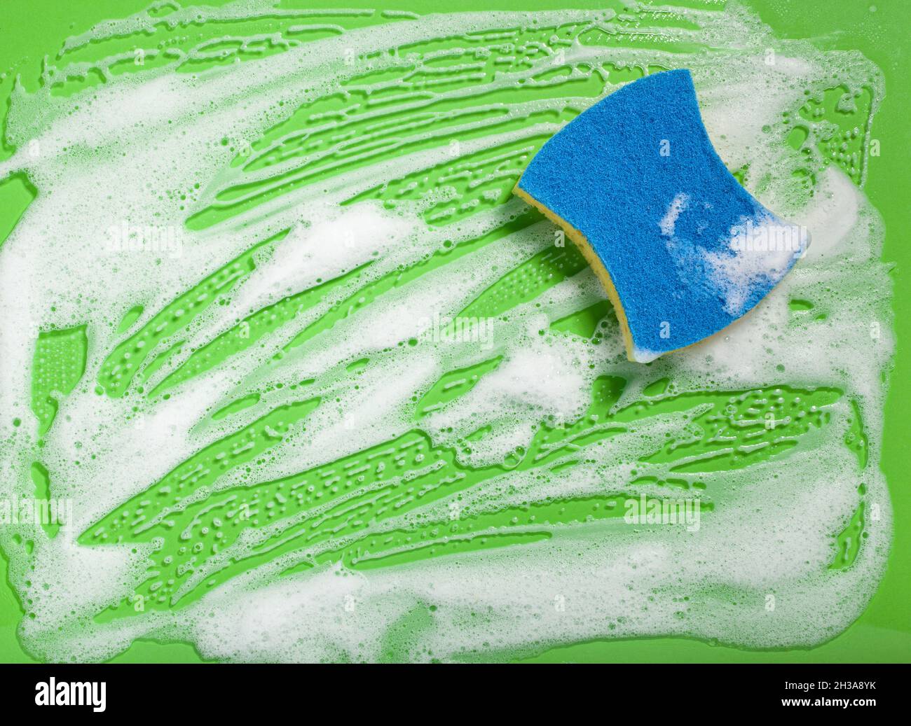 cleaning sponge wiping foam soap suds on green background, household ...
