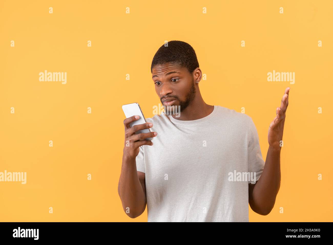 Terrible connection. Angry black guy looking at his smartphone in rage ...