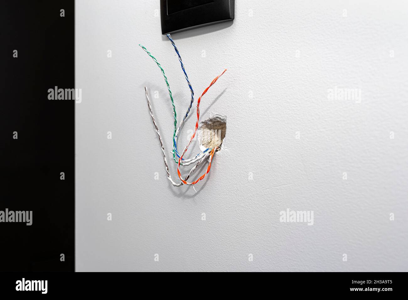 Eight colored cables from the intercom stick out from the wall of the ...