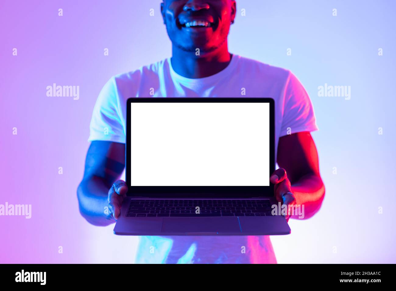 Closeup of young black guy holding laptop with empty white screen in ...