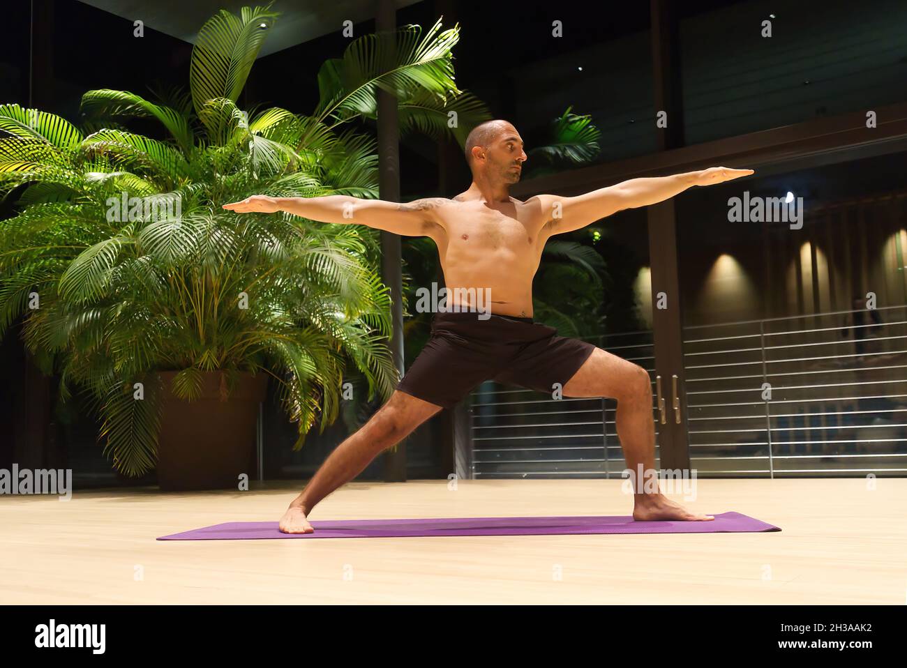 Middle aged handsome Caucasian male performs a yoga position indoors ...