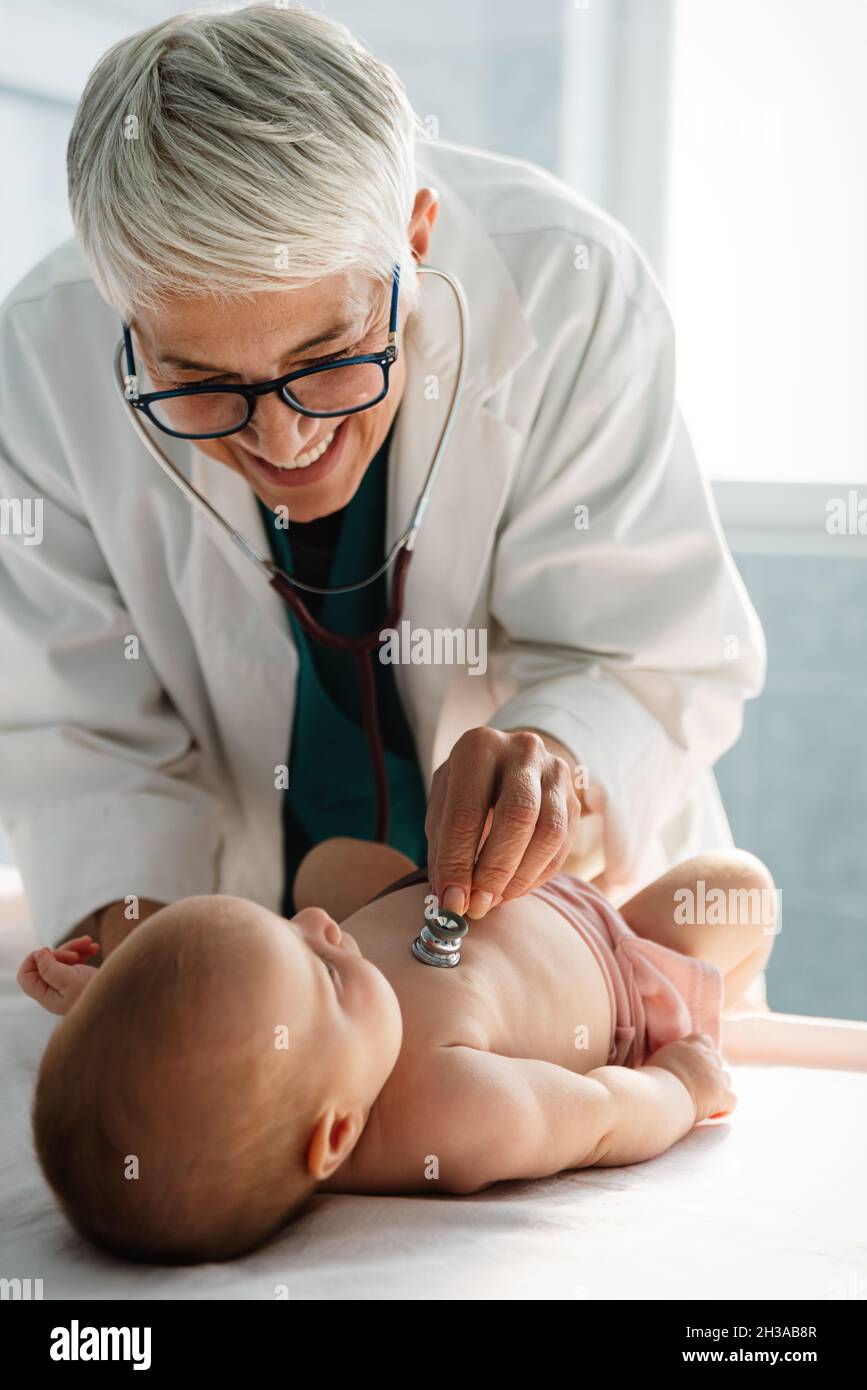 Happy pediatrician doctor with baby checking possible heart defect ...