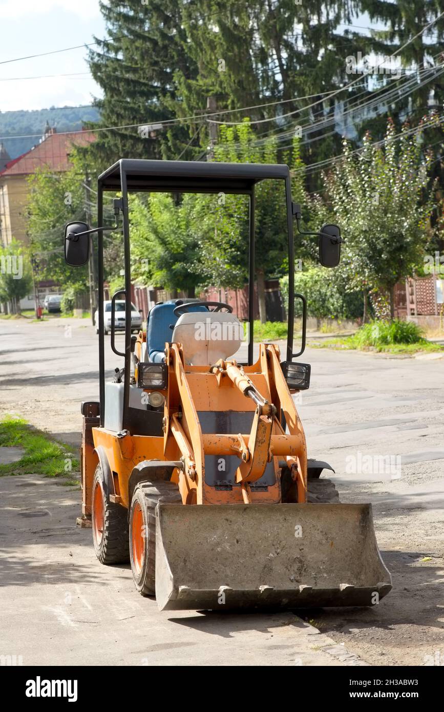 Orange excavator vehicle stopped on a road Stock Photo - Alamy