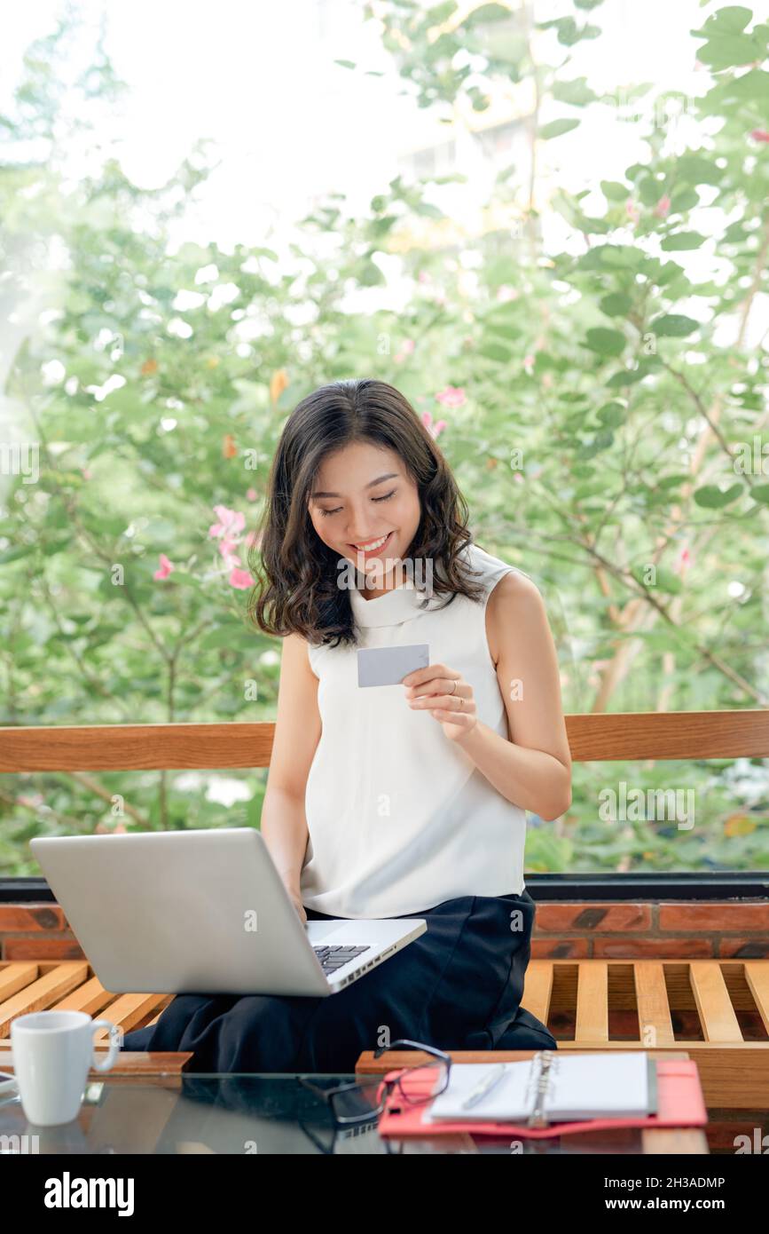 Beautiful young woman working on laptop computer while sitting at the ...