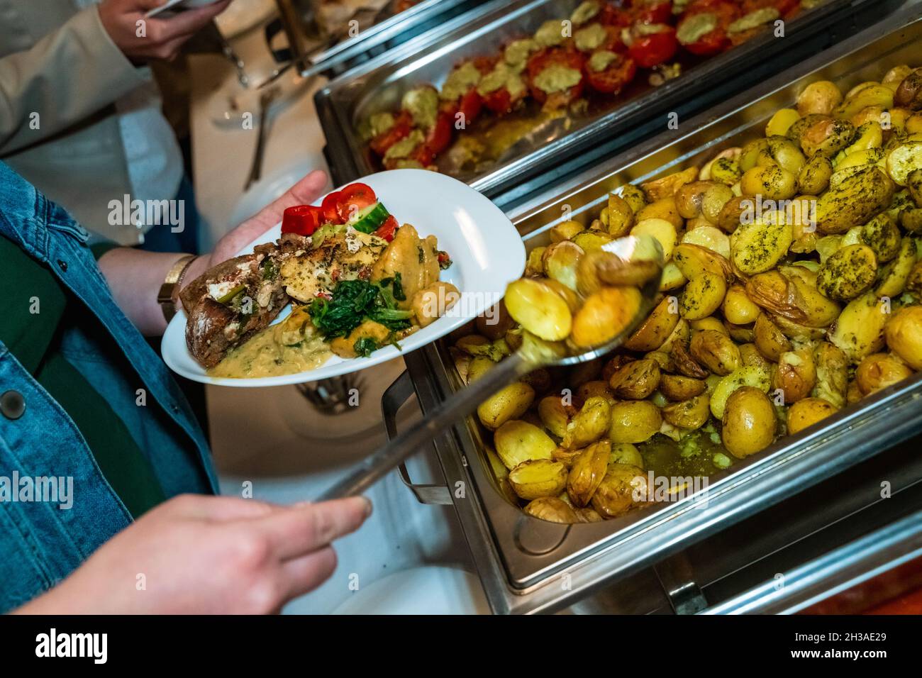 High-angle shot of a man adding cooked potatoes to his plate in a ...
