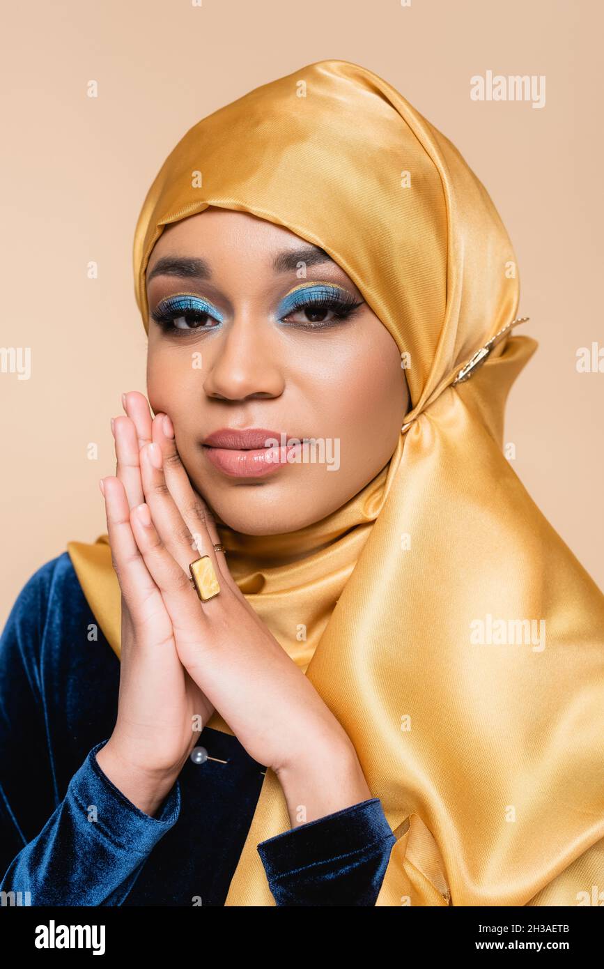 muslim woman in yellow hijab with bright makeup and golden ring looking ...