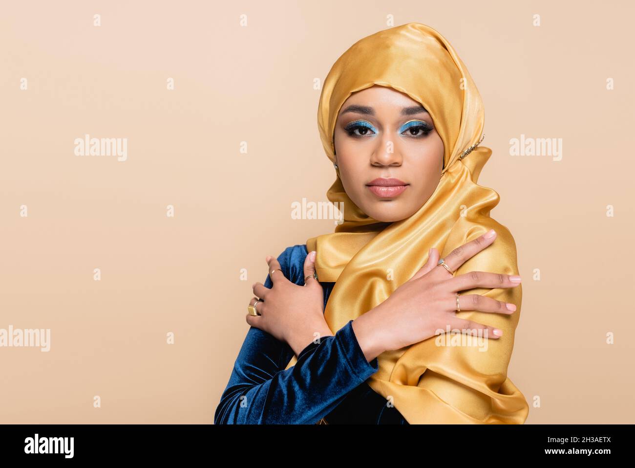 young muslim woman in yellow hijab posing with crossed arms isolated on ...
