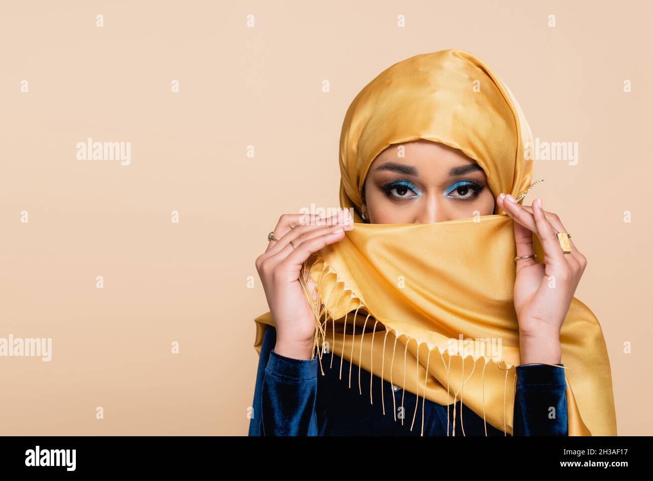 muslim woman with bright eye makeup covering face with hijab isolated ...