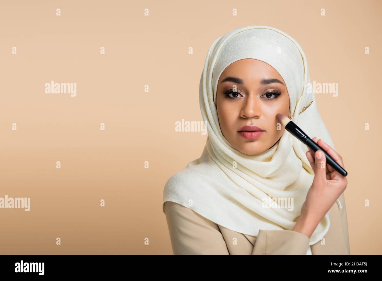 young muslim woman in hijab applying makeup foundation isolated on ...