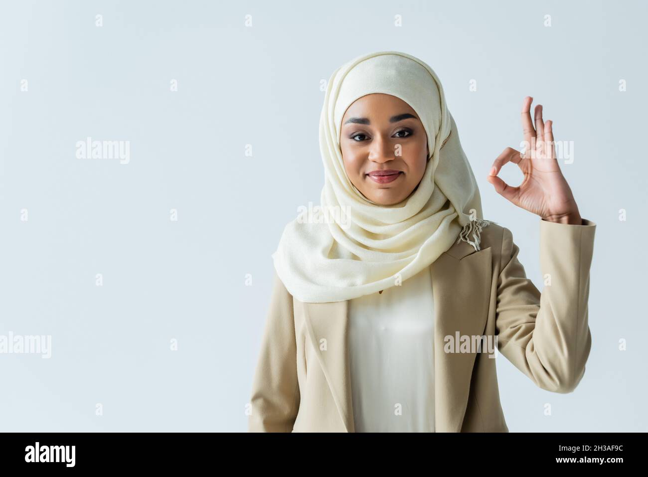 happy muslim woman in hijab showing ok sign and smiling isolated on ...