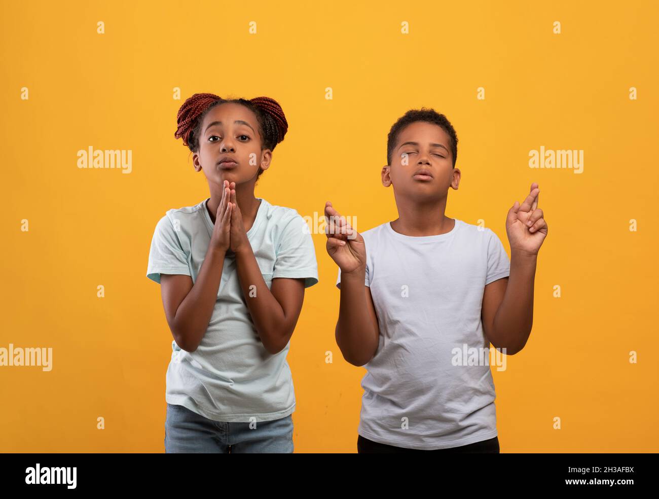 Innocent african american kids praying on yellow Stock Photo - Alamy