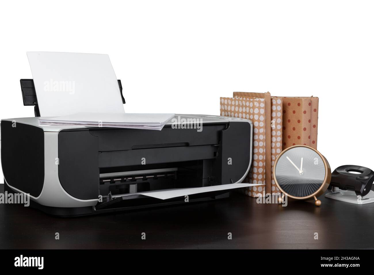 Printer and stack of books on black table against white background ...