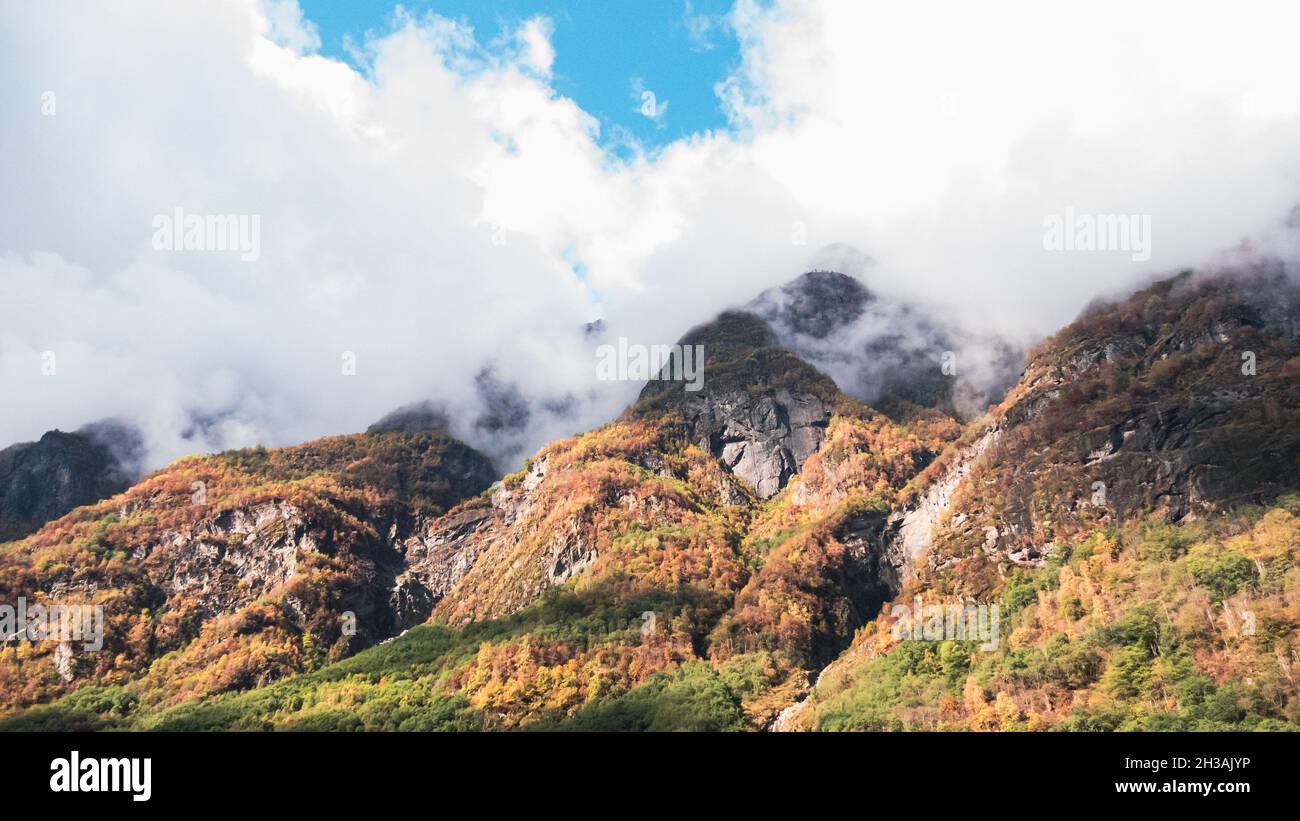Breathtaking view of mountain peaks covered in clouds under sunlight ...