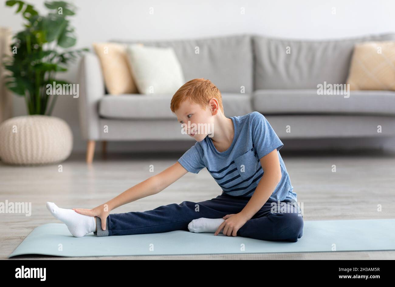 Cute redhead boy stretching on fitness mat at home Stock Photo - Alamy