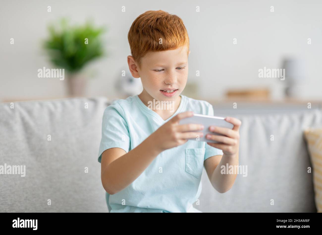Joyful redhead boy playing video games, using cellphone Stock Photo - Alamy
