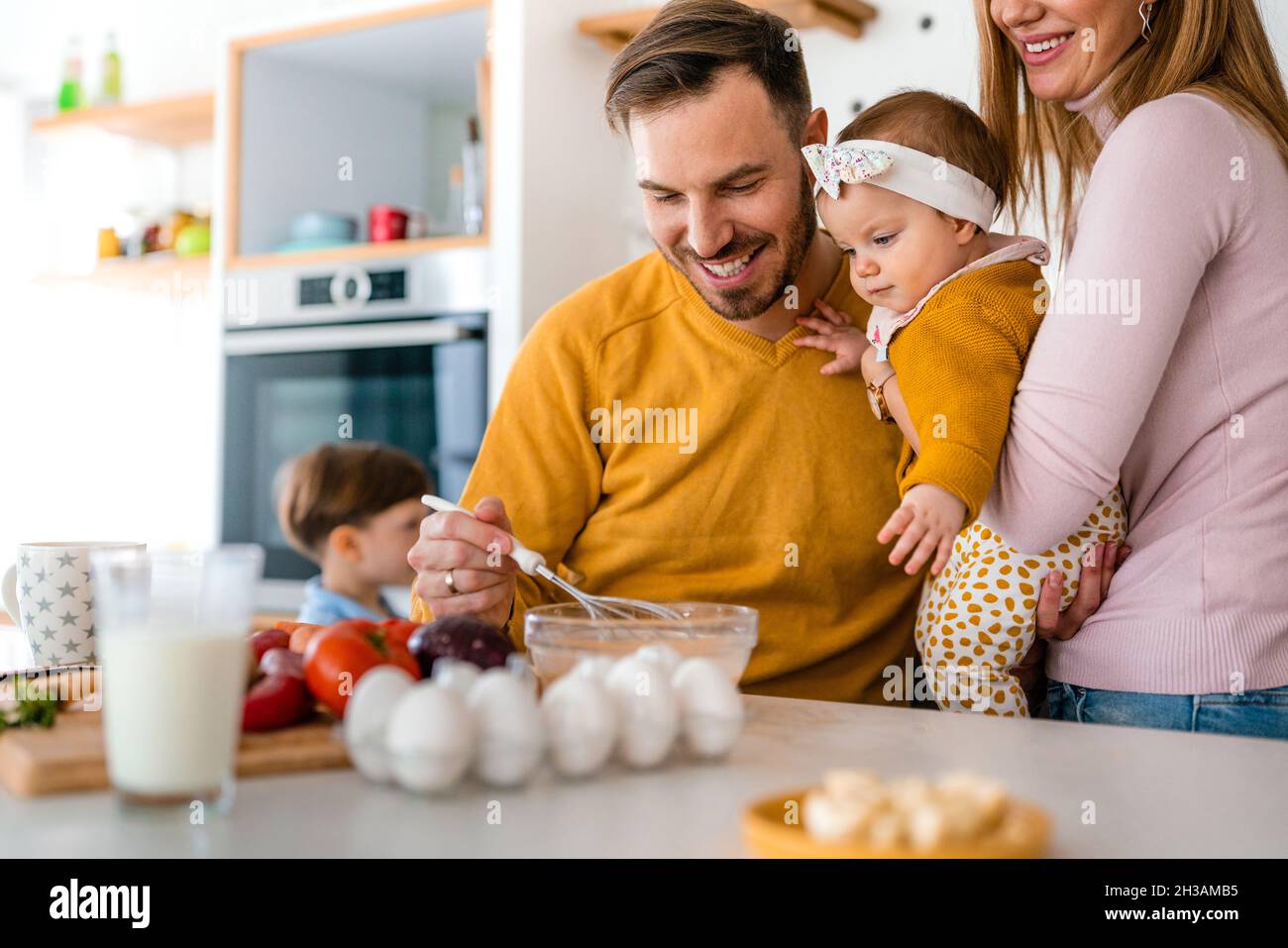 Little girl and his parents having fun and cooking together in the ...