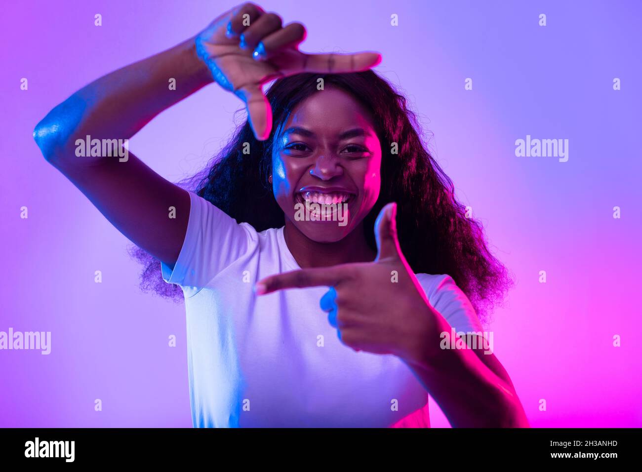Happy black woman making picture frame with fingers, looking at camera ...