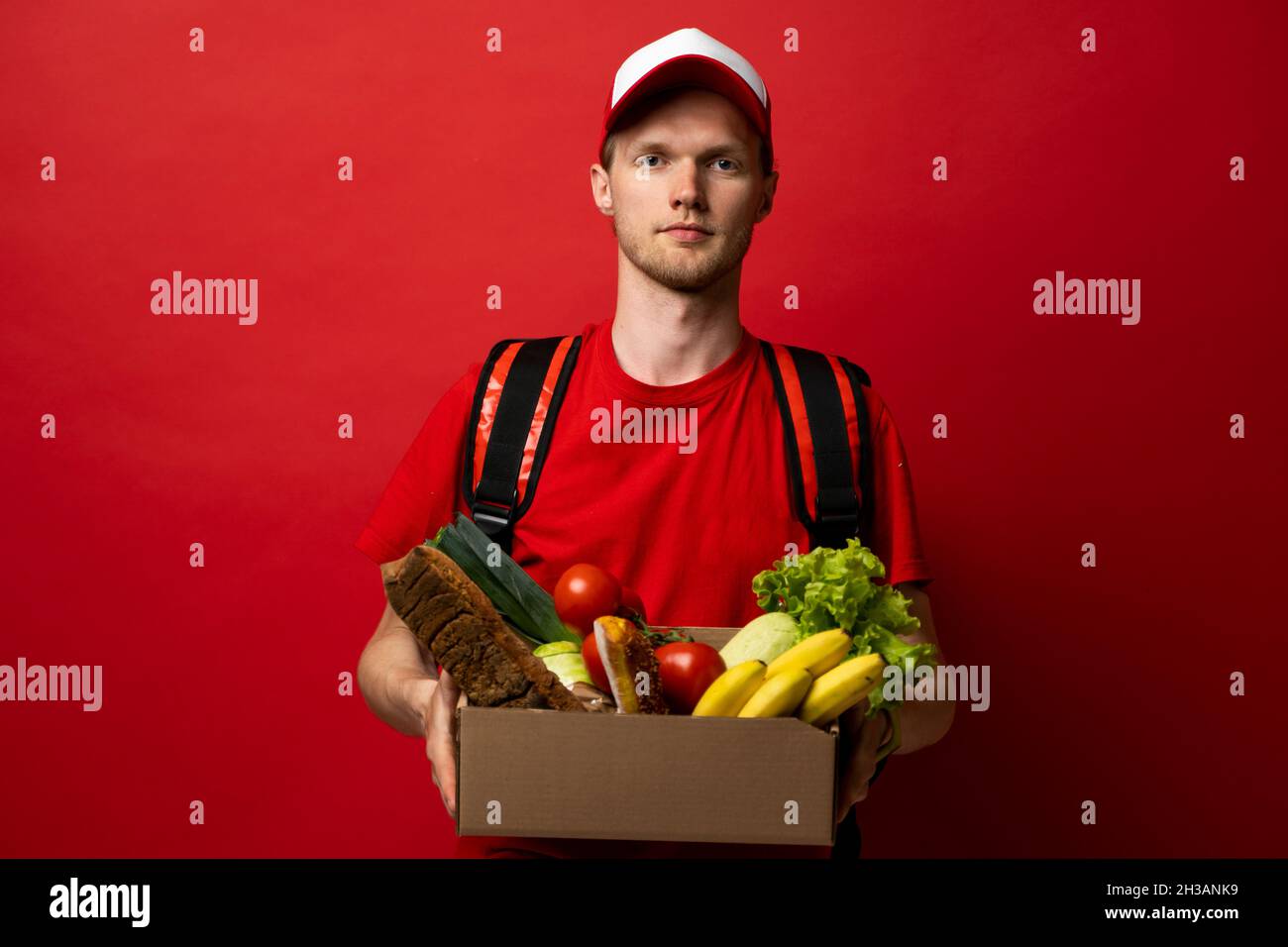 Delivery Concept. Portrait of pleased delivery man in red uniform ...