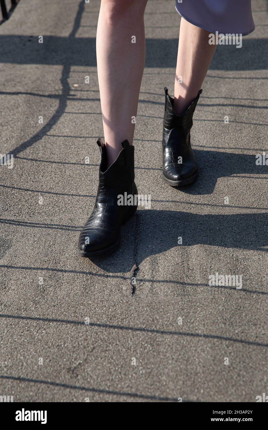 Legs of white woman in black boots on the pavement Stock Photo - Alamy