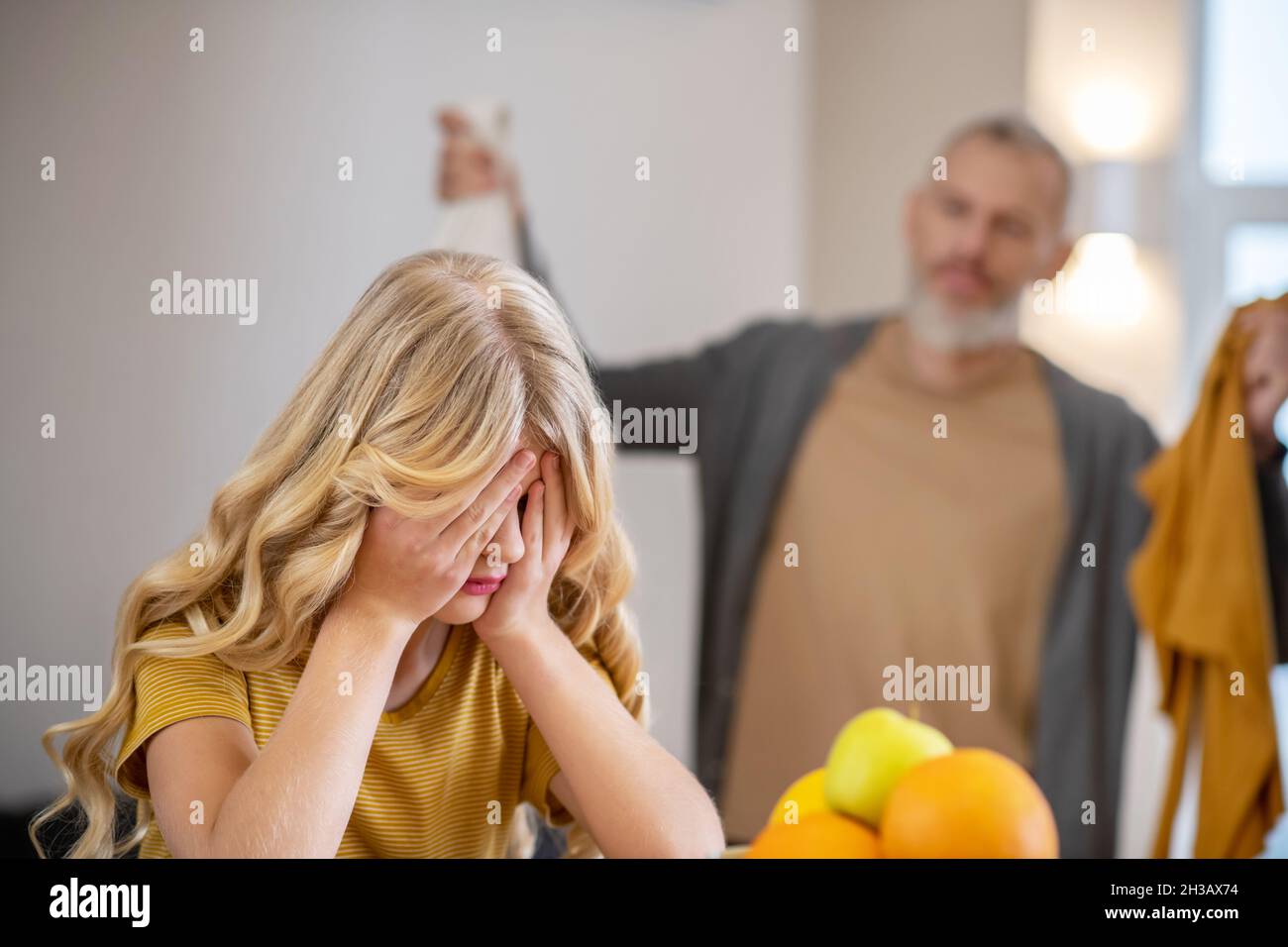 A blonde cute girl feeling frustrated while her father shouting at her ...