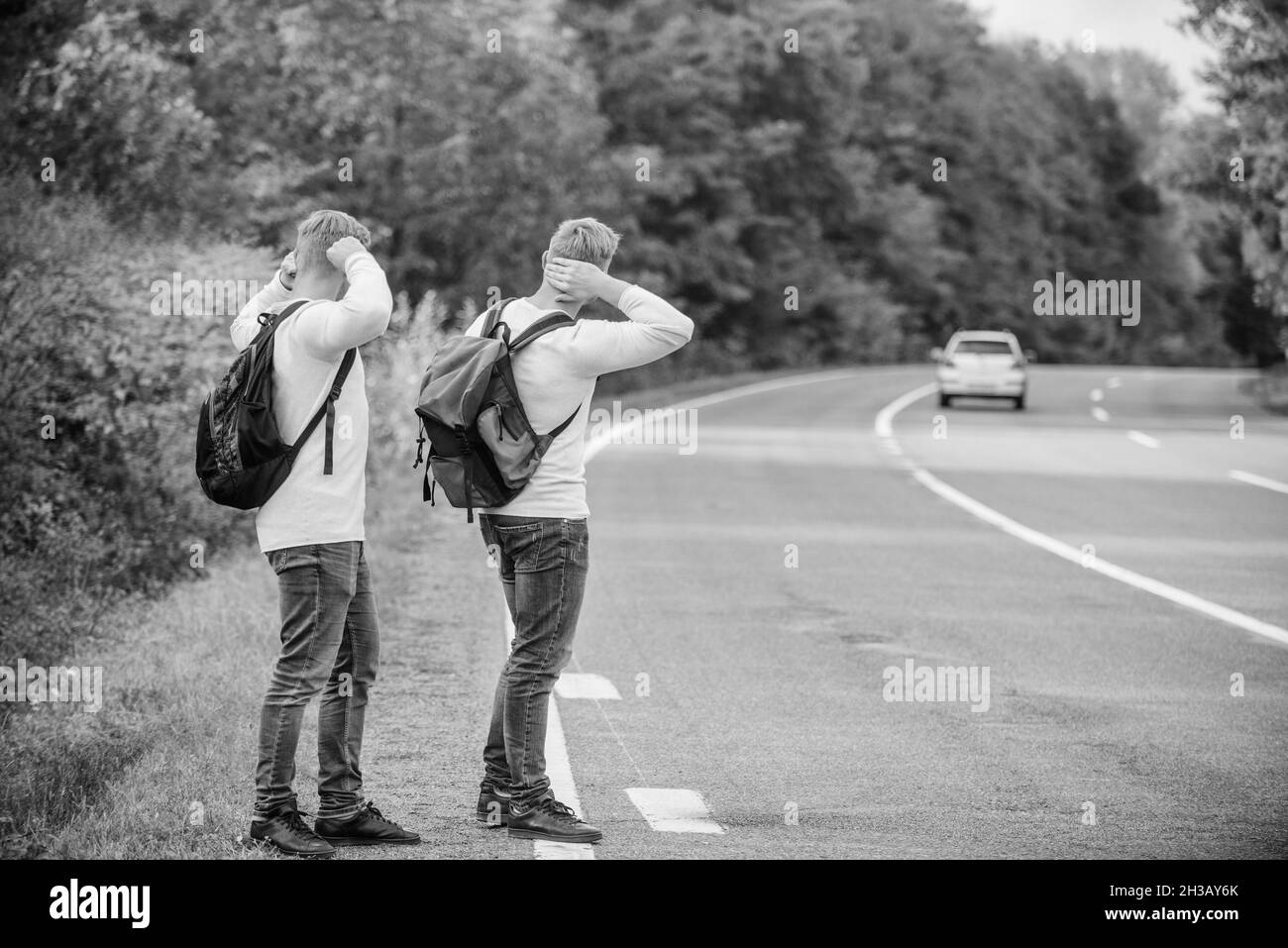 Try to stop some car. Travel and transport concept. Twins men at edge ...