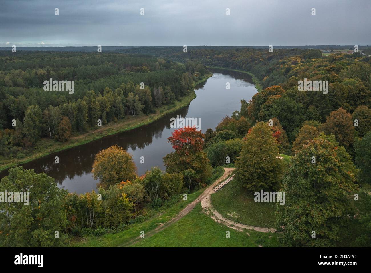 Punia mound in Lithuania with green grass and autumn trees background ...