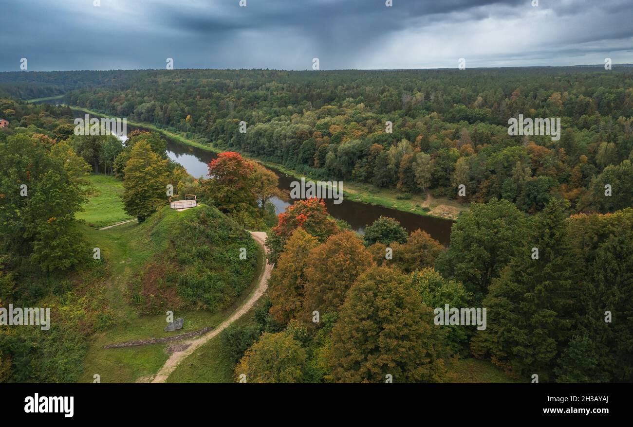 Punia mound in Lithuania with green grass and autumn trees background ...