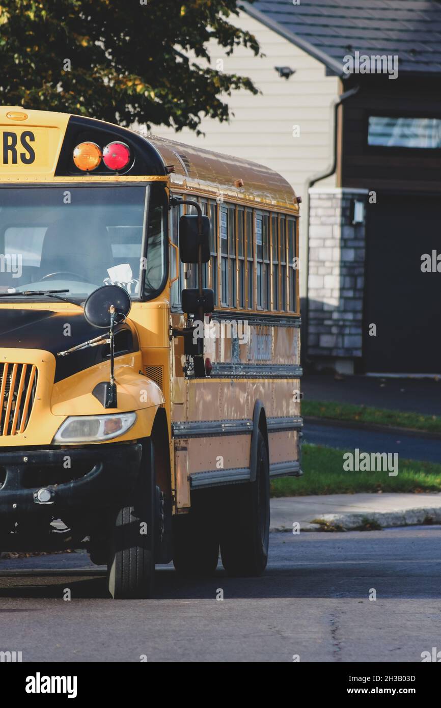 Vertical shot of a school bus waiting for children in a suburb street ...