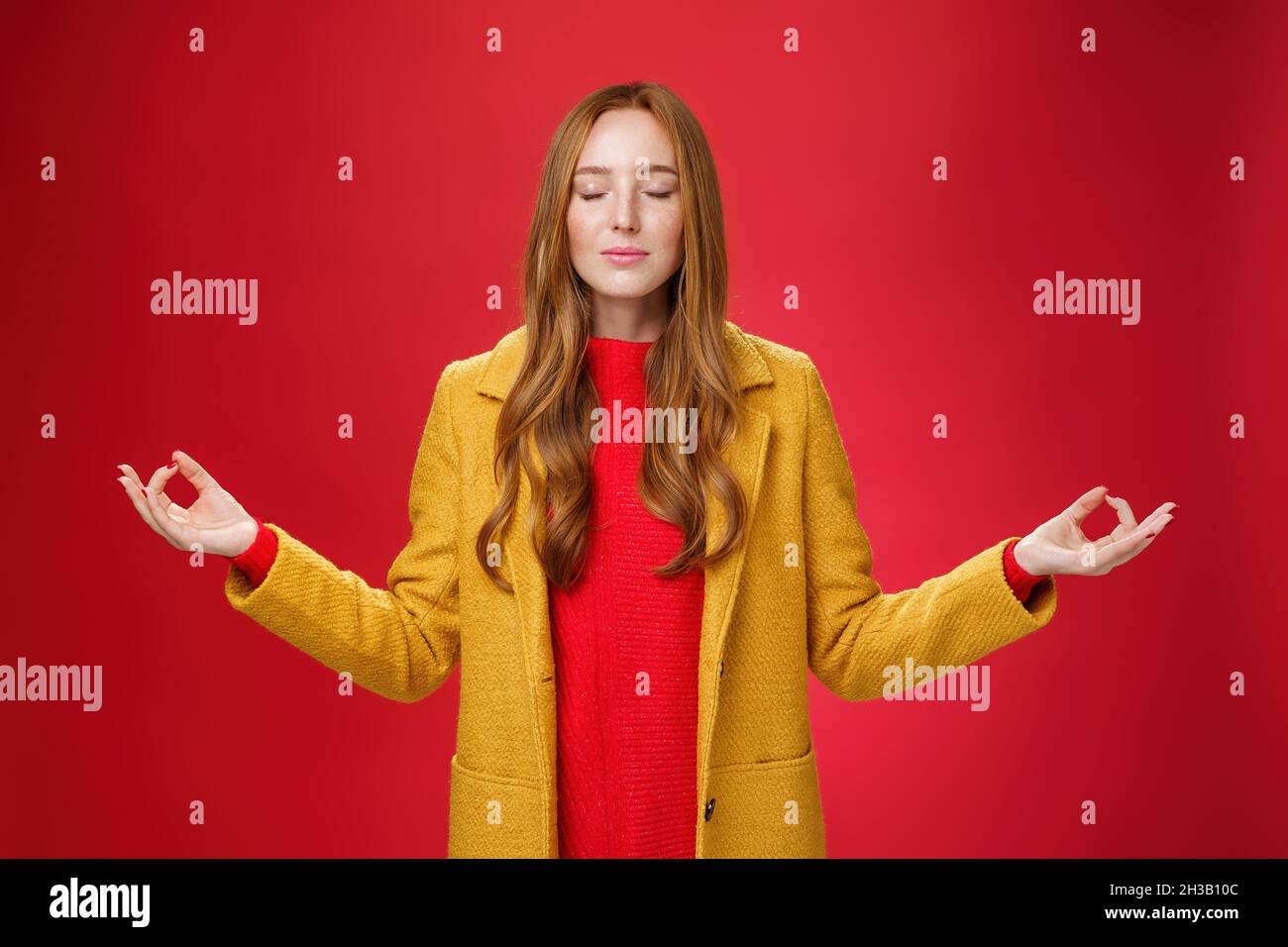 Girl keep calm releasing stress with meditation, posing in yellow coat ...