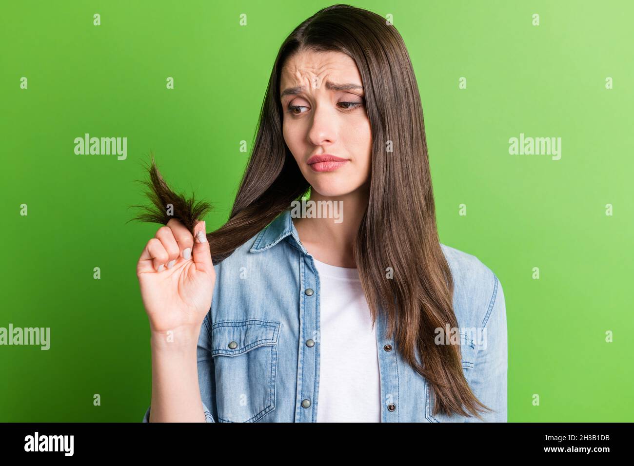 Portrait of attractive sad girl holding dry hair ends choose shampoo ...