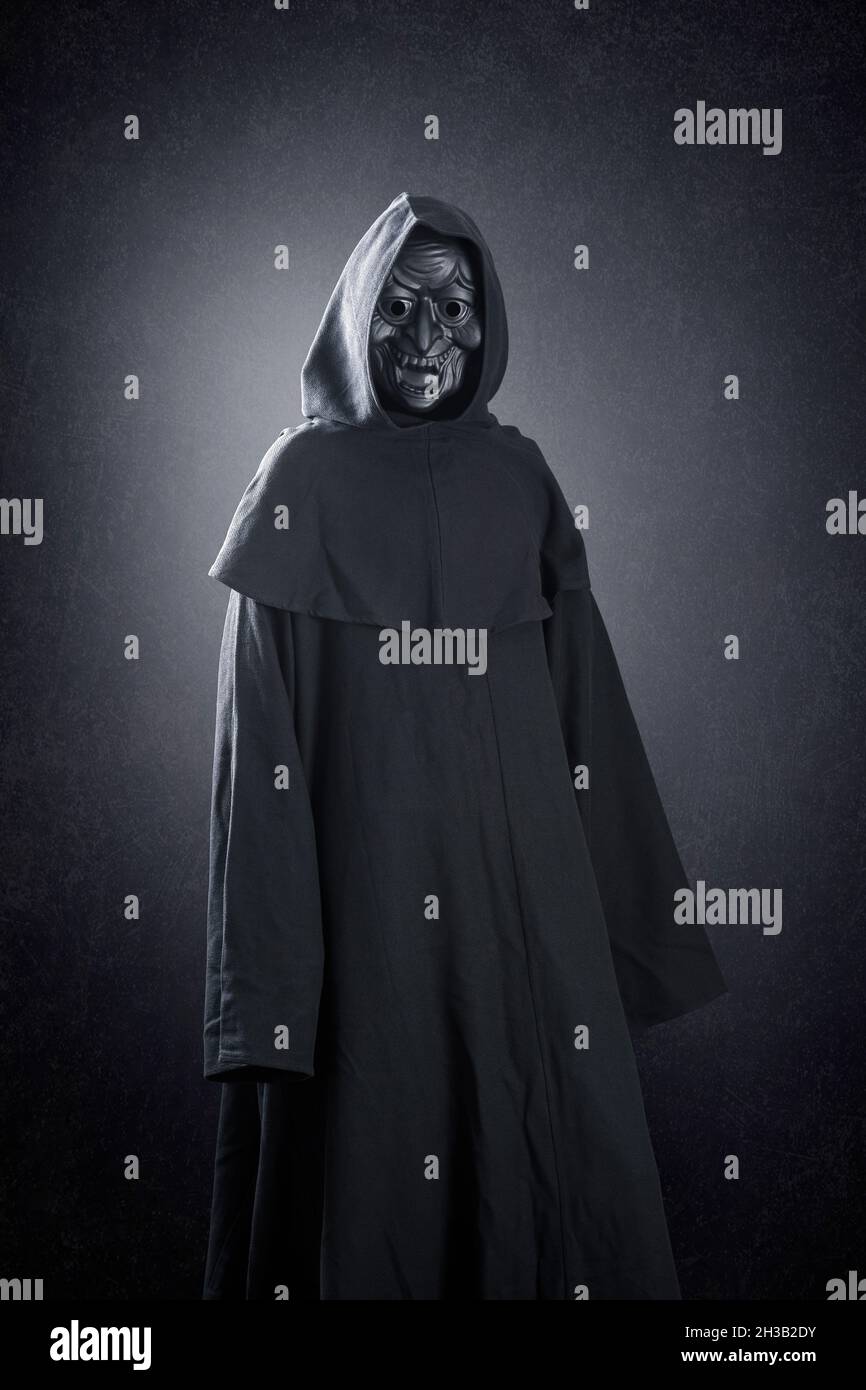 Spooky figure with hooded cape over dark misty background Stock Photo ...