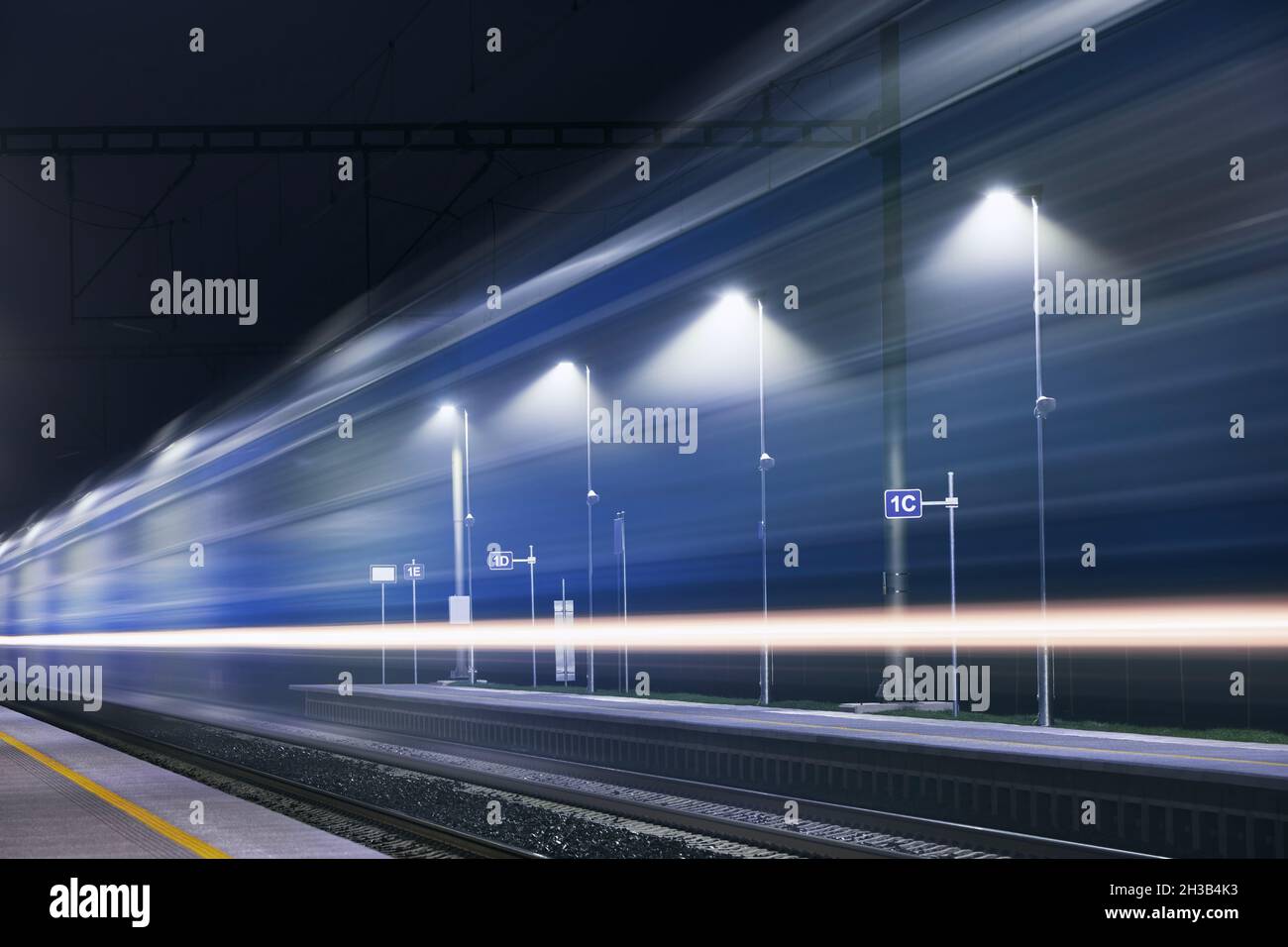 Railway at night. Light trails of passenger train at illuminated ...