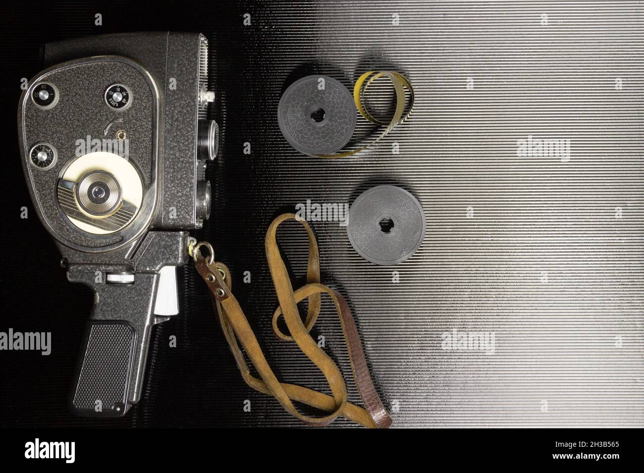 Old amateur movie camera and spools of roll film on black background ...