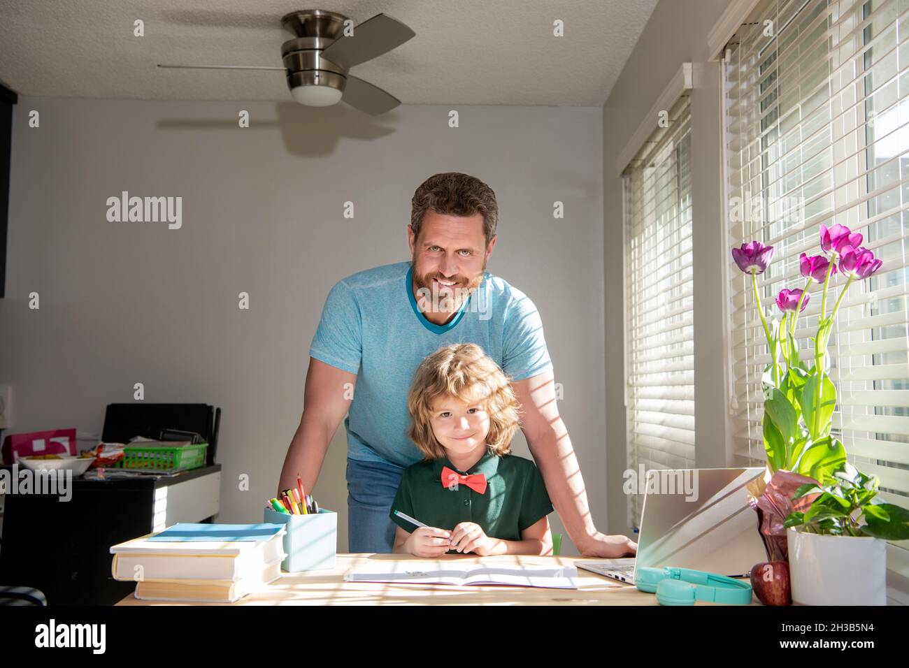 cheerful daddy writing school homework with his kid son in classroom ...