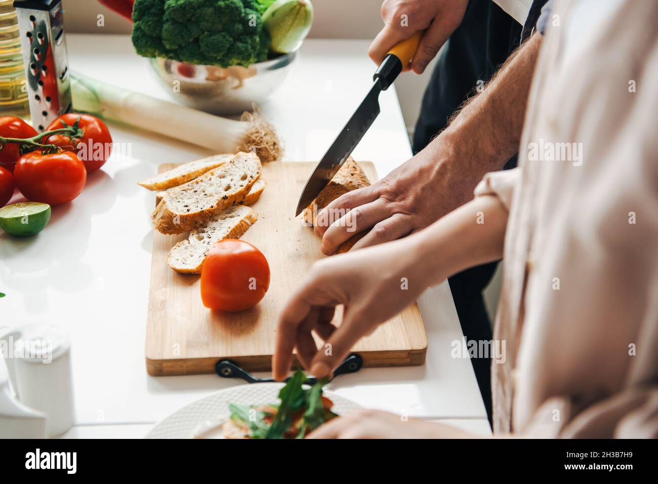 Couple preparing lunch together, making salad and cutting bread ...